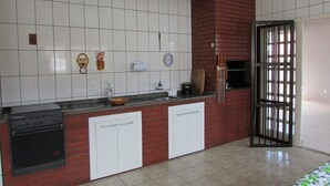 Uma cozinha com armários brancos, forno preto, parede de tijolos e painel de azulejos.
