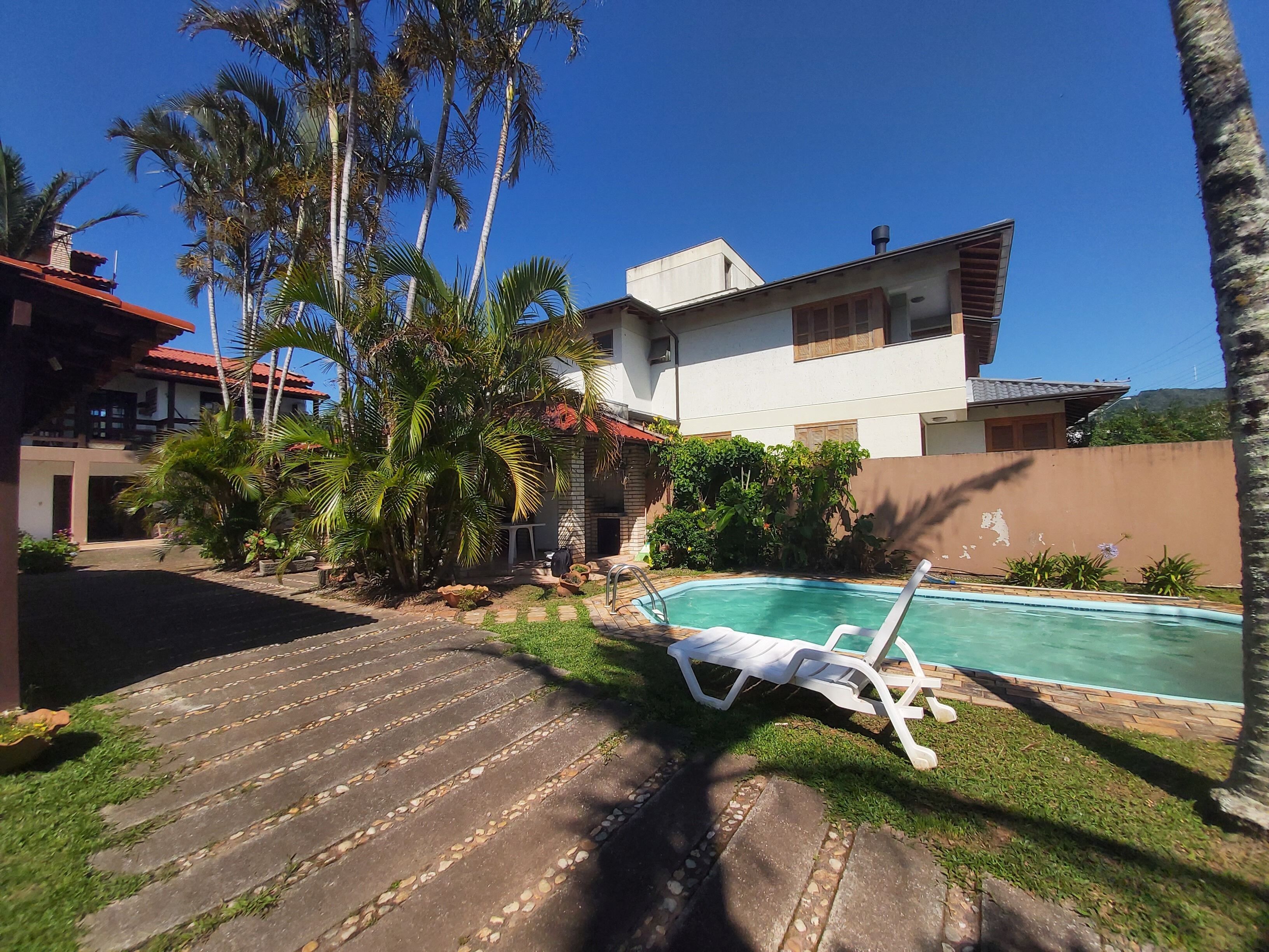 Área residencial com piscina, palmeiras e calçada.