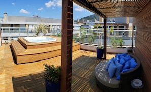 Um terraço no telhado com hidromassagem, assentos de madeira e plantas em vasos.