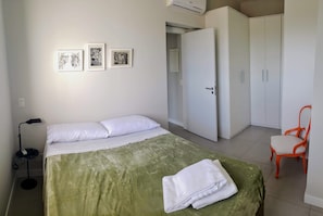 Um quarto bem arrumado, com uma cama, uma cadeira e um guarda-roupa.