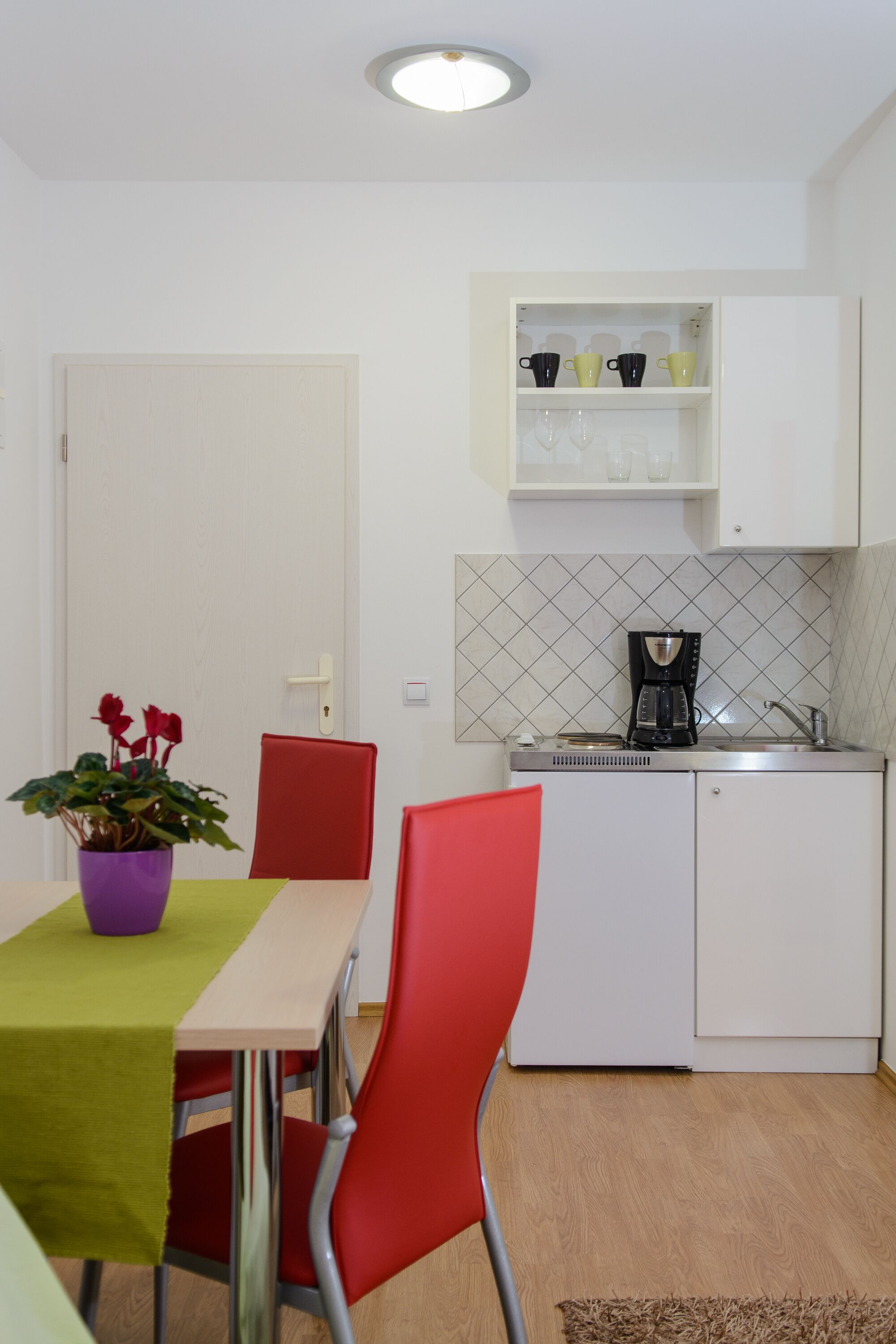Uma cozinha compacta com cafeteira, pia e armário sobre o balcão.