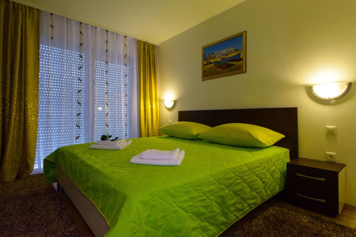 Quarto de hotel com cama bem arrumada, mesa de cabeceira e um quadro na parede.