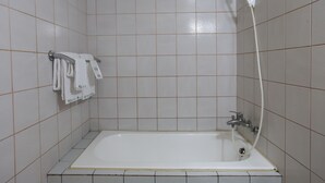 Casa de banho com banheira, chuveiro e toalheiro com toalhas.