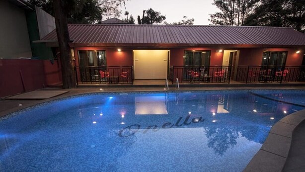 Piscina com o nome "Onella" na água, rodeada por um edifício com telhado vermelho e área de estar coberta.