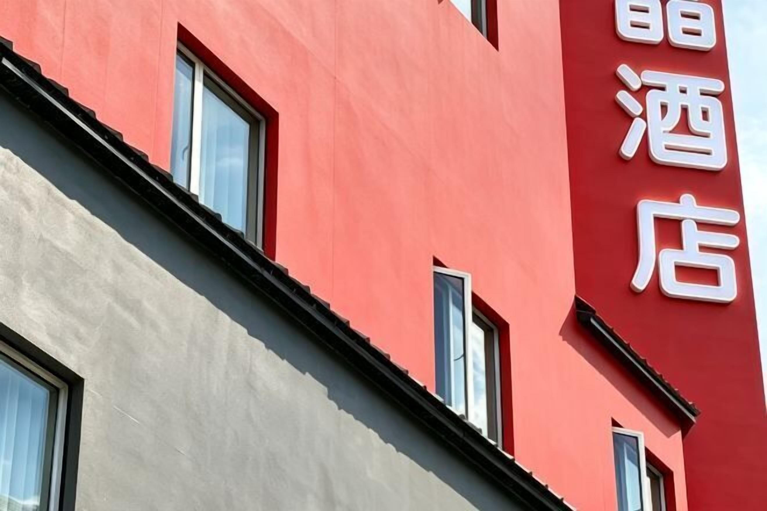 Um edifício com fachada vermelha e uma placa indicando um hotel.