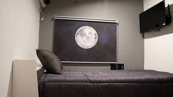Quarto com cama, TV na parede e um mural com estrelas e lua.