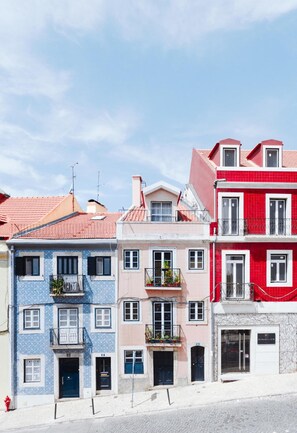Uma fileira de edifícios coloridos com estilos arquitetônicos distintos, incluindo um prédio vermelho com fachada visível.