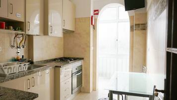 Um frigorífico, um forno, uma placa de cozinha, utensílios de cozinha