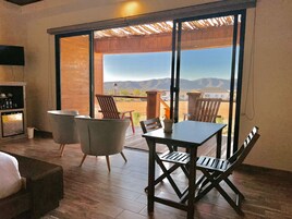 Um quarto aconchegante com piso de madeira, uma mesa de jantar com cadeiras, um sofá e uma televisão na parede.