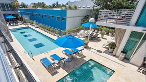 Área de piscina no terraço com duas piscinas, espreguiçadeiras e guarda-sóis.