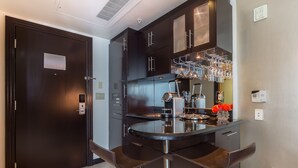 Uma cozinha moderna com armários escuros, uma ilha de aço inoxidável com banquetas e um escorredor de copos.