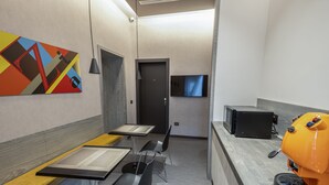 Quarto de hotel moderno com sofá, máquina de café e televisão na parede.