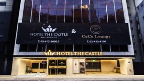 Um hotel moderno com uma placa de destaque para 'Hotel The Castle' e 'CoCo Lounge'.