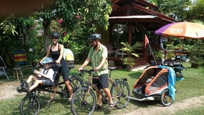 Um jardim com um gazebo, um carrinho de bebê e bicicletas.