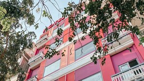 Um hotel com fachada vermelha, varandas e uma placa com a inscrição 'EROS HOTEL'.