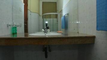Casa de banho com lavatório, espelho e porta-toalhas.