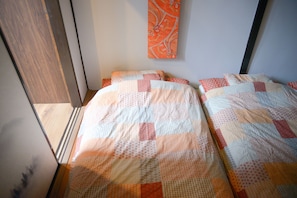 Quarto com duas camas, cada uma coberta por um edredom de retalhos.