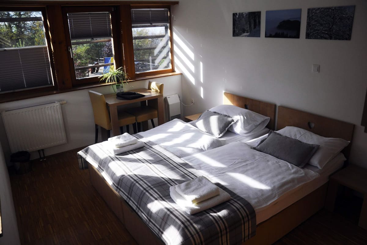 Quarto com cama, escrivaninha e radiador.