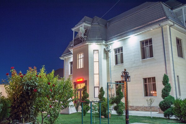 Uma casa de dois andares com gramado bem cuidado e antena parabólica no telhado.