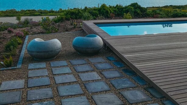 Área da piscina com vista para o mar e colinas.