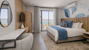 Quarto moderno com uma cama grande, uma escrivaninha e uma televisão.
