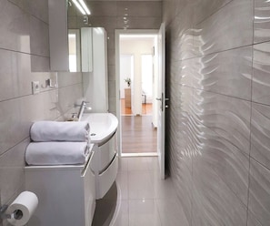 Uma casa de banho moderna com sanita, lavatório e suporte para toalhas.