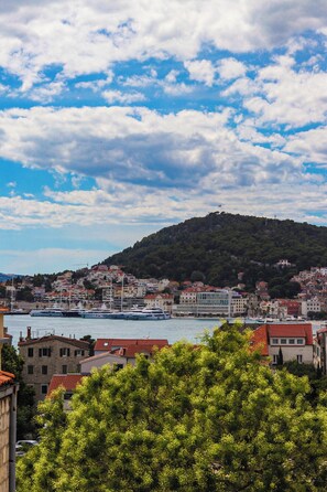 Uma vila costeira com edifícios, uma colina e barcos na água.