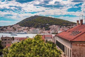 Uma vila costeira com edifícios, uma colina e barcos na água.