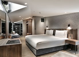 Quarto moderno com uma cama grande, mesas de cabeceira, guarda-roupa e televisão.