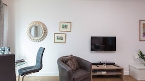 Uma sala de estar moderna com uma televisão de tela plana, um espelho redondo e quadros na parede.