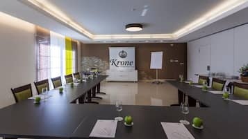 Uma sala de conferências com uma mesa comprida, cadeiras e um banner com a inscrição 'Krone'.