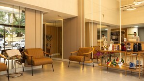 Um hall de hotel moderno com poltronas de couro, balcão de recepção e espaço para café.
