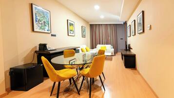 Quarto de hotel moderno com área de jantar, sofá e obras de arte nas paredes.