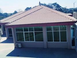 Um edifício com telhado de telhas, janelas amplas e um pequeno aparelho de ar condicionado.