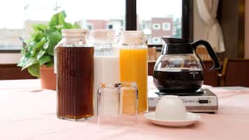 Uma mesa com diversos recipientes de bebida, uma cafeteira e um pequeno prato.