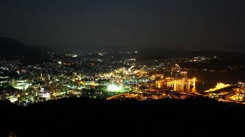 Paisagem urbana noturna com edifícios iluminados e uma ponte em destaque.