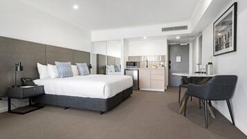 Quarto de hotel moderno com uma cama grande, mesas de cabeceira, uma escrivaninha e uma cadeira.
