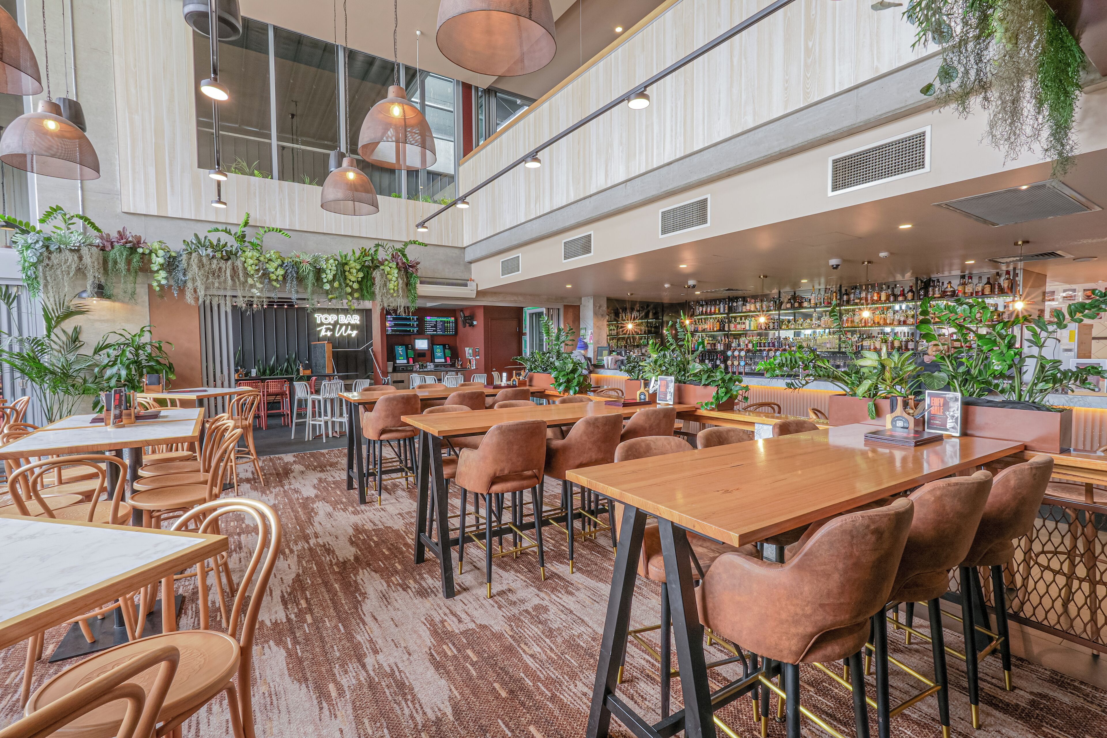 Um espaço amplo para o bar, com diversas opções de assento e várias plantas.