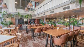 Um espaço amplo para o bar, com diversas opções de assento e várias plantas.