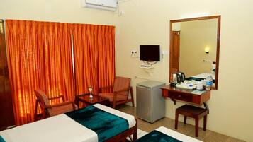 Quarto de hotel com duas camas, uma escrivaninha com espelho, televisão e frigorífico.