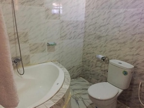 Casa de banho com banheira, sanita e chuveiro.