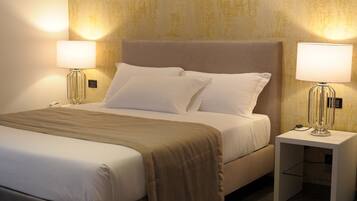 Quarto de hotel com cama, duas mesas de cabeceira com abajures e parede com textura.