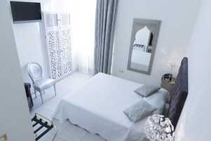 Quarto com cama, cadeira, guarda-roupa, espelho e mesa de cabeceira.