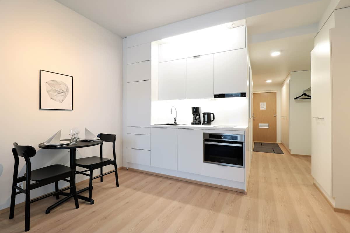 Uma cozinha compacta com área de refeições, cafeteira e um quadro na parede.