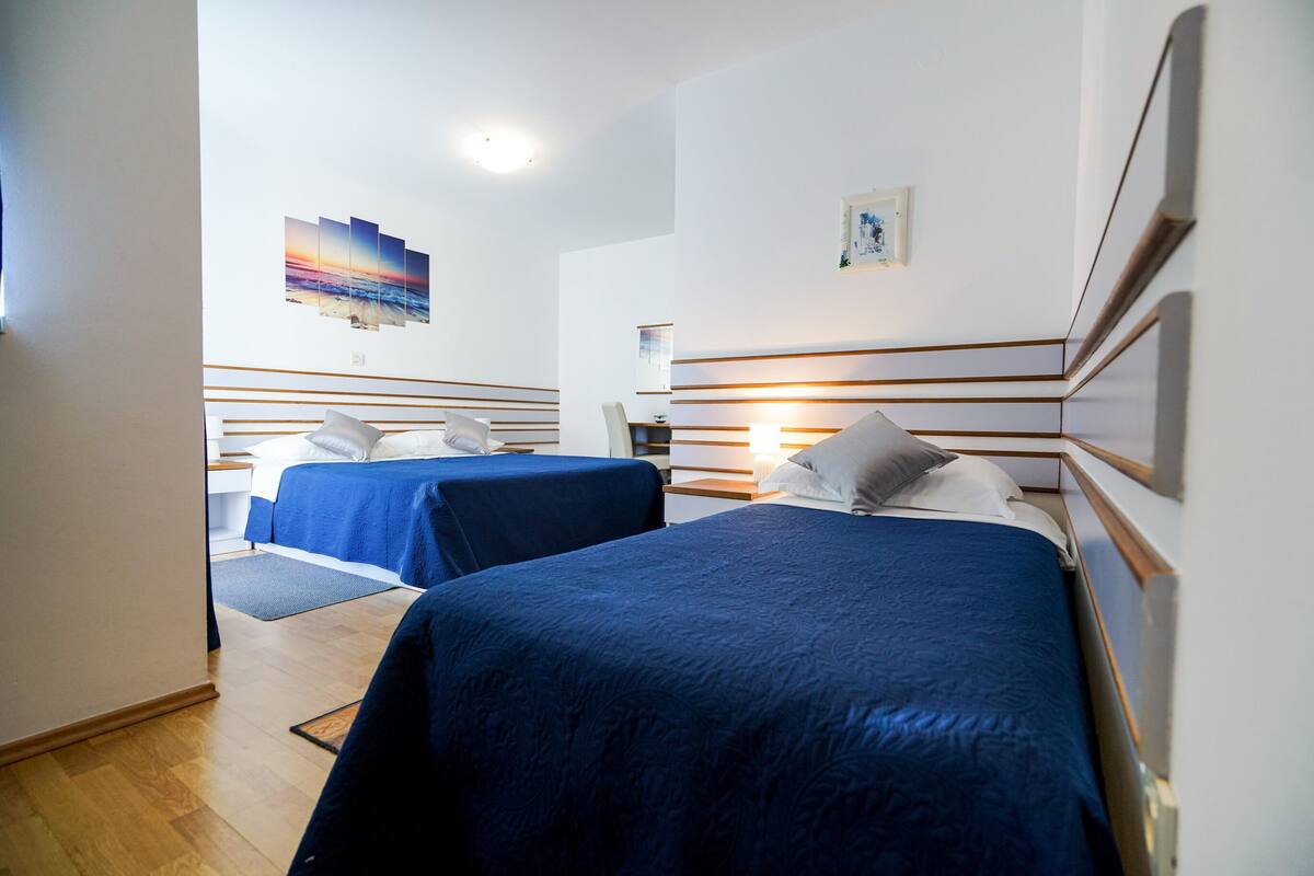 Quarto de hotel com duas camas, cabeceiras de madeira e uma pintura na parede.