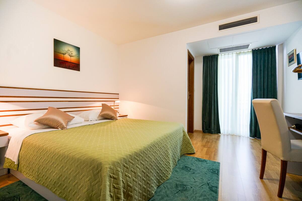 Quarto de hotel com cama, escrivaninha e cadeira.