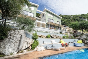 Uma casa moderna de dois andares com piscina, área de estar externa e vista para a paisagem ao redor.