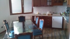 Uma cozinha com armários de madeira, mesa de jantar de vidro e cadeiras azuis.