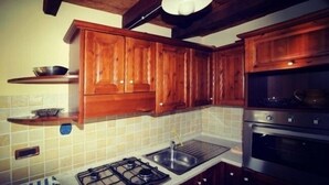 Uma cozinha com armários de madeira, fogão a gás, pia e forno vitrocerâmico.
