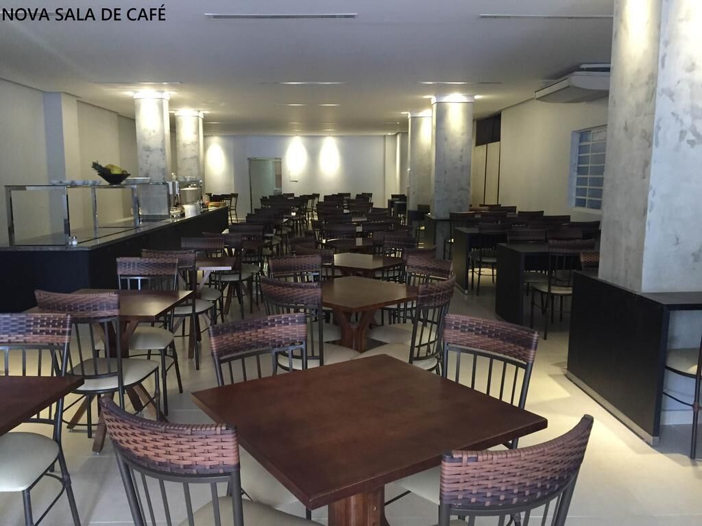 Um café espaçoso, com várias mesas e cadeiras, um balcão e design moderno.